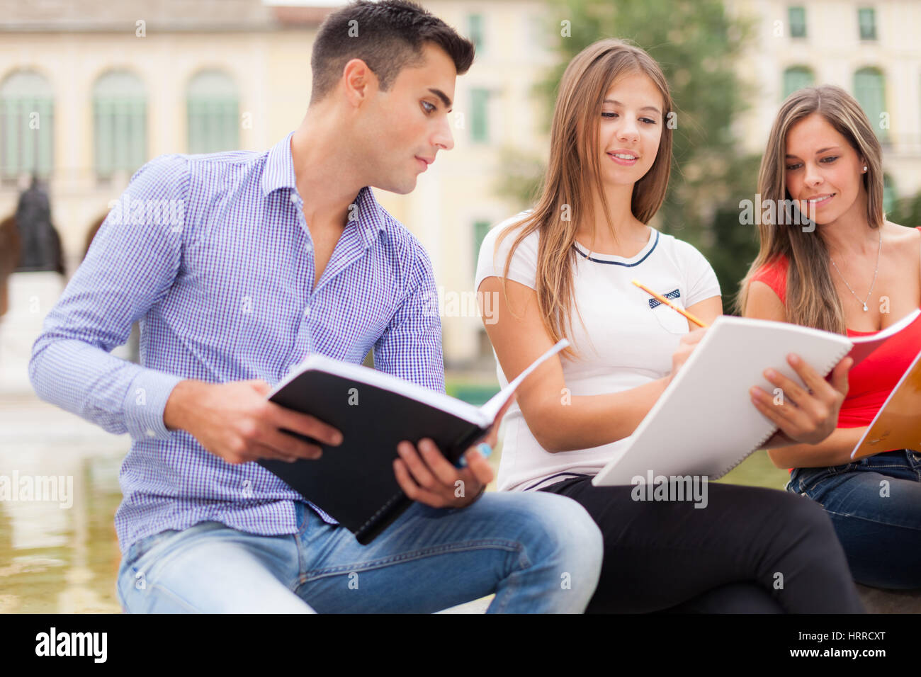Students sharing their notes while sitting outdoors Stock Photo - Alamy