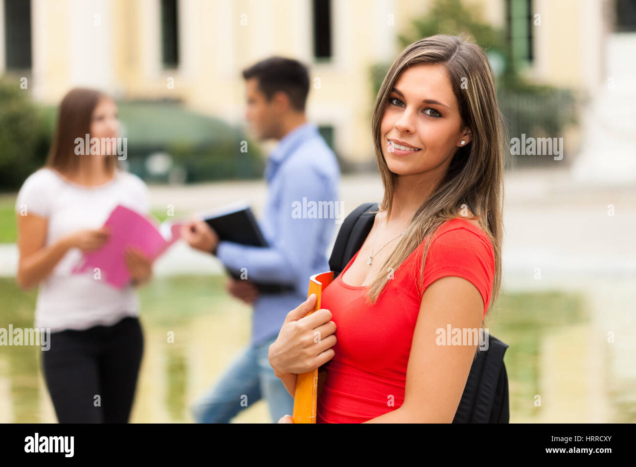Smiling female student portrait, group of classmates in the background ...