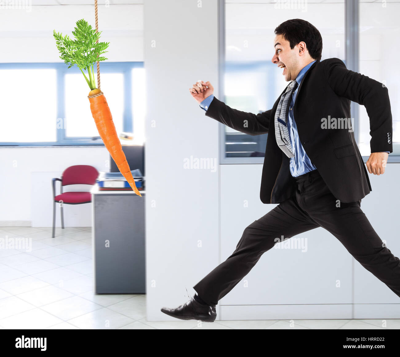 Businessman trying to take a carrot. Motivation concept Stock Photo - Alamy
