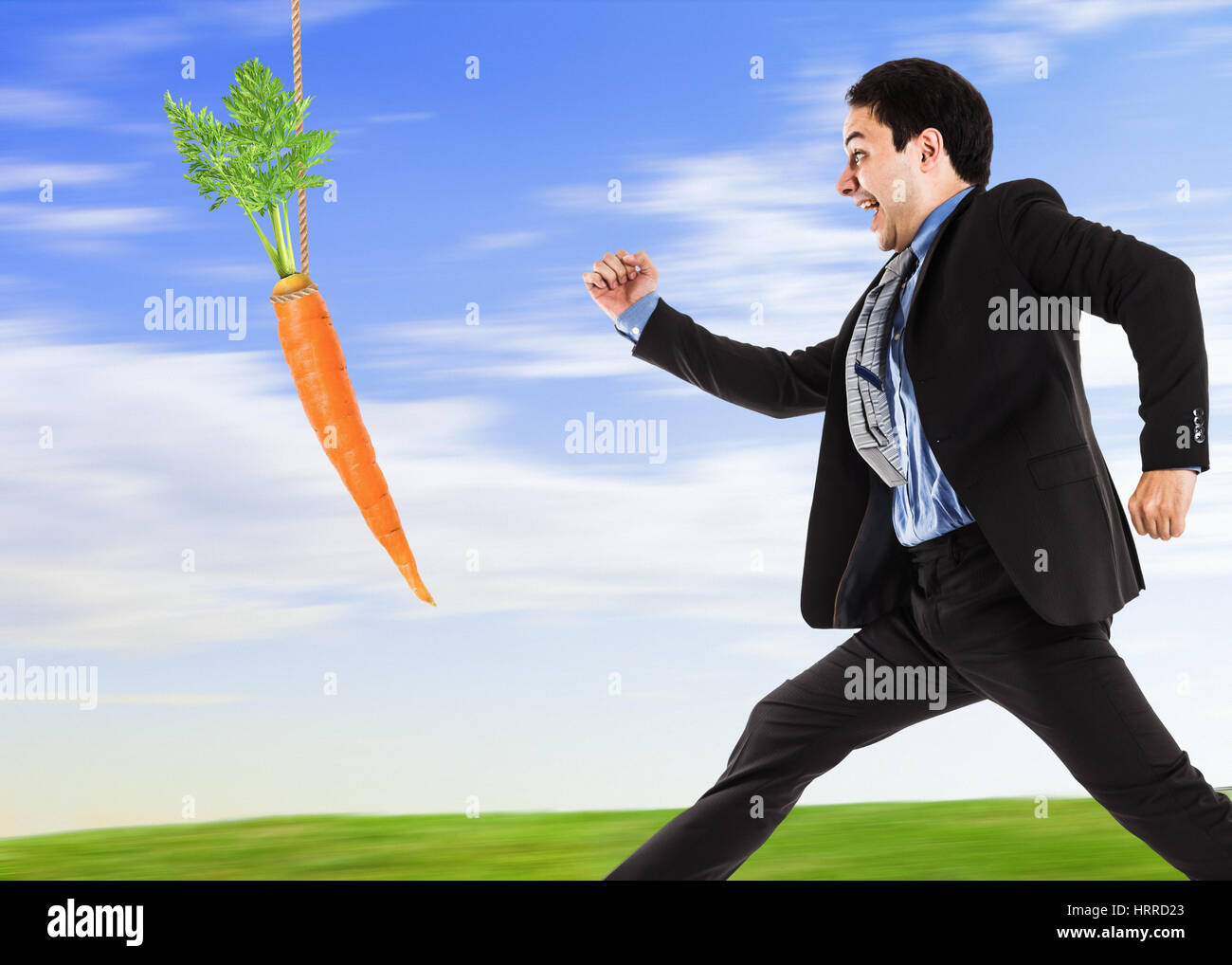Businessman trying to take a carrot. Motivation concept Stock Photo - Alamy