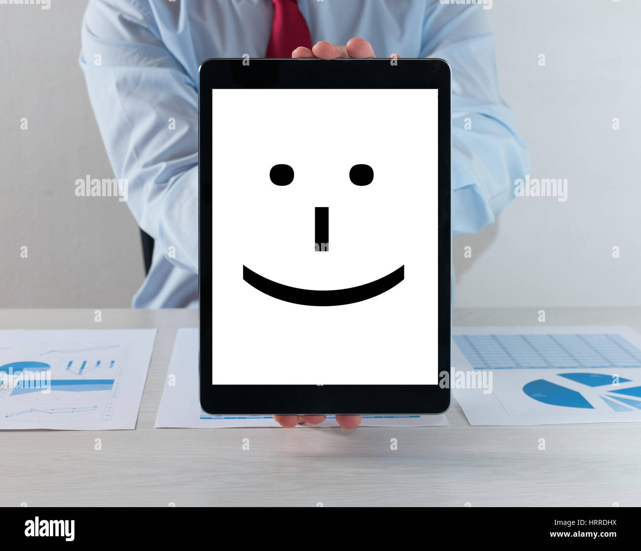 Businessman showing a smiling tablet Stock Photo - Alamy