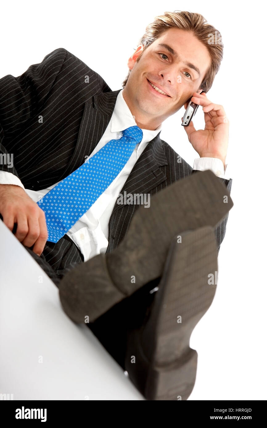Confident businessman on the phone with his feet on the table ...