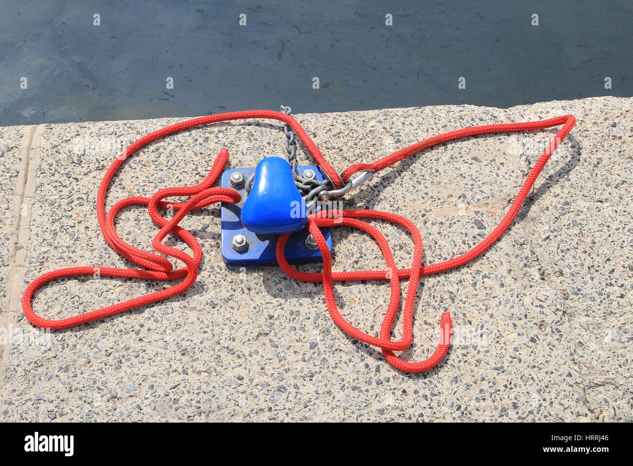 Blue harbor bollard with red rope on a concrete harbour quayside Stock ...