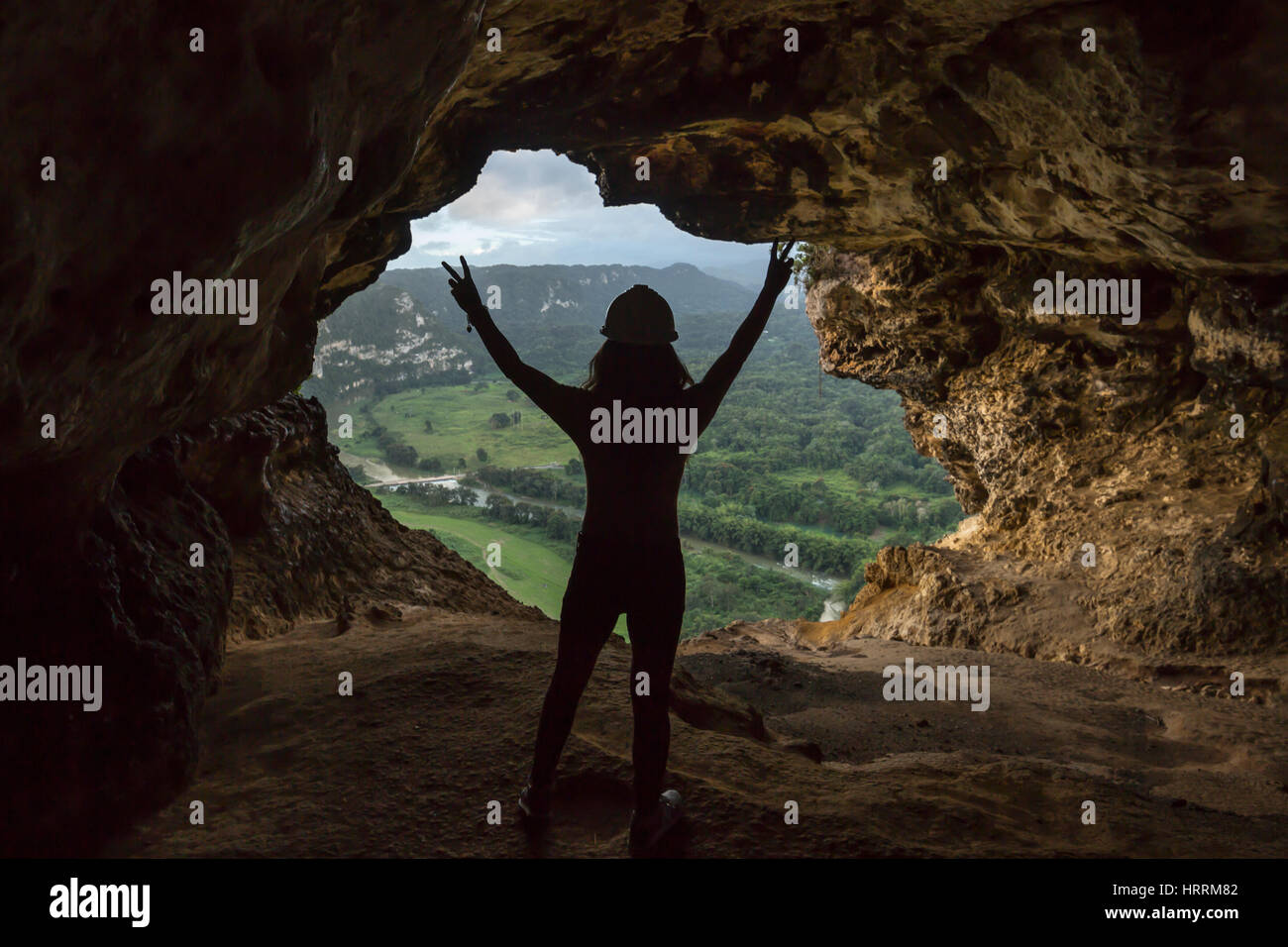 YOUNG WOMAN STANDS RAISING ARMS IN VICTORY CAVE WINDOW OVERLOOKING RIO ...