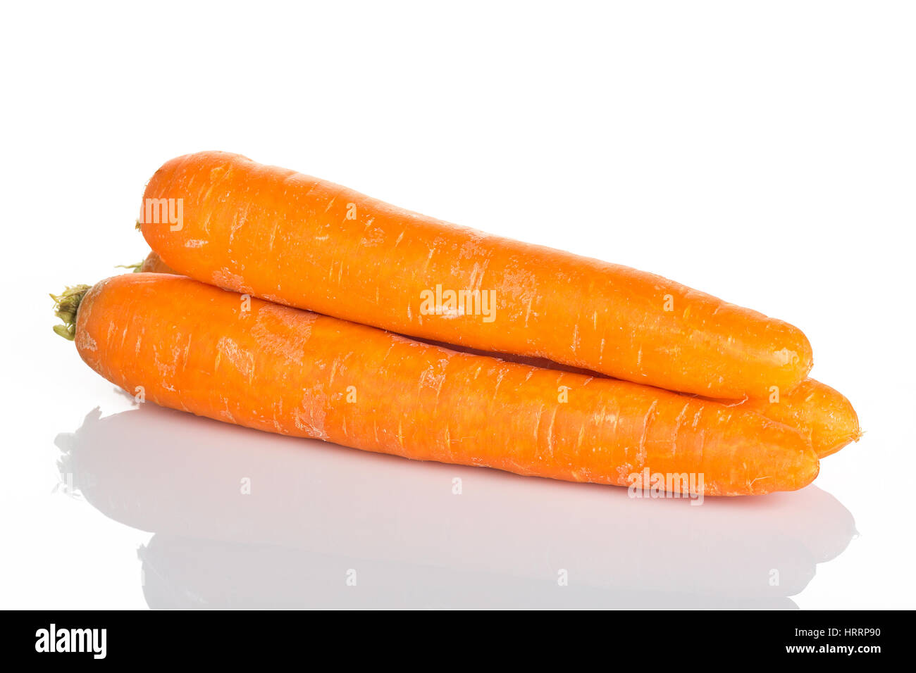 Three carrots on a white background with reflection Stock Photo - Alamy