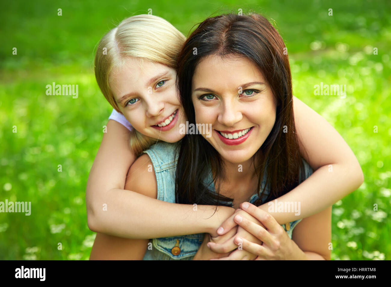 hugging happy mother and daughter for a walk in the park on light green background Stock Photo ...