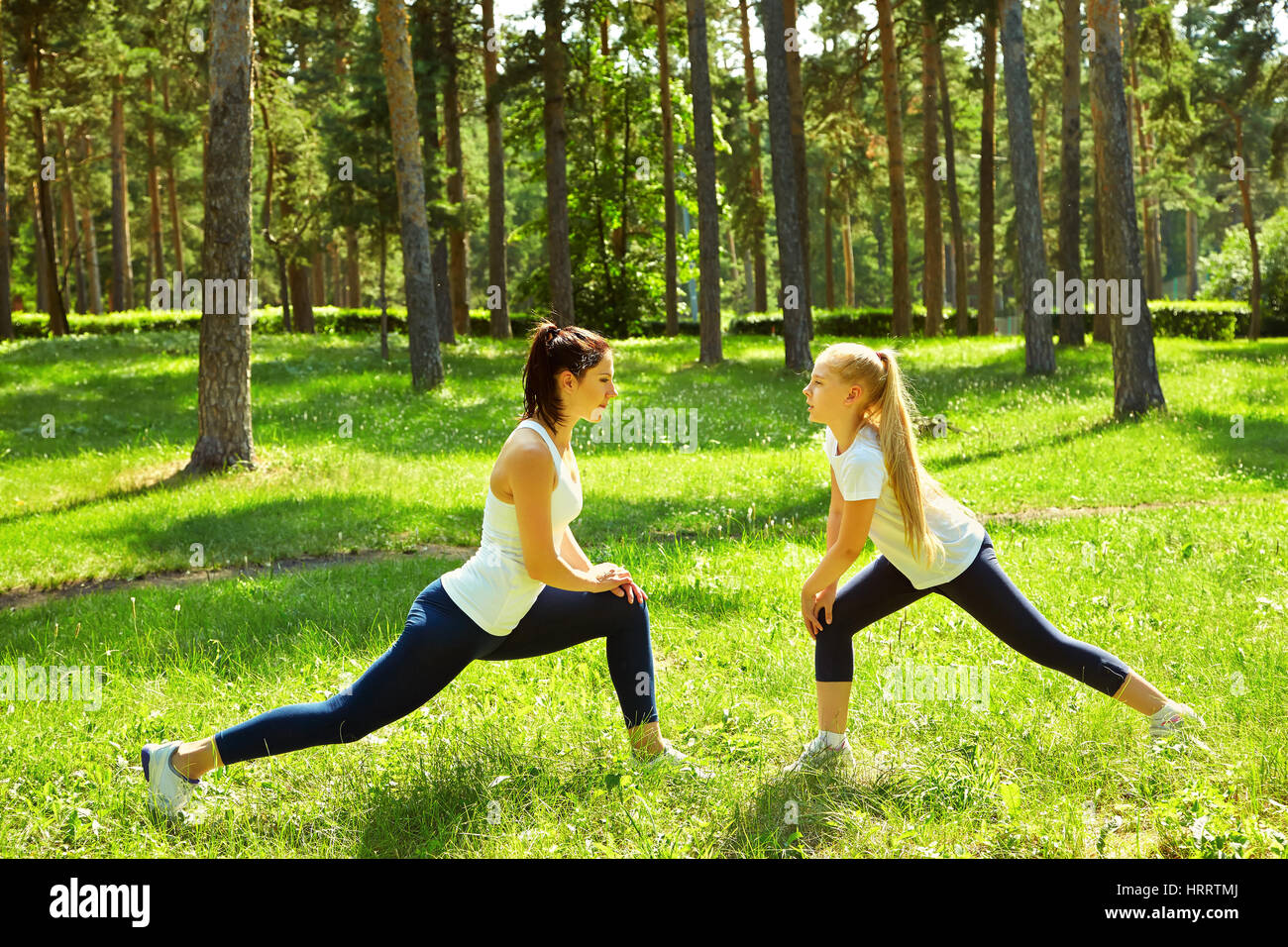 sporty mother and daughter. woman and child training in the park ...