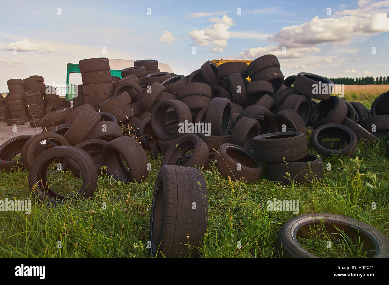Stack of used tyres lay on green grass background. Pile of used tires ...