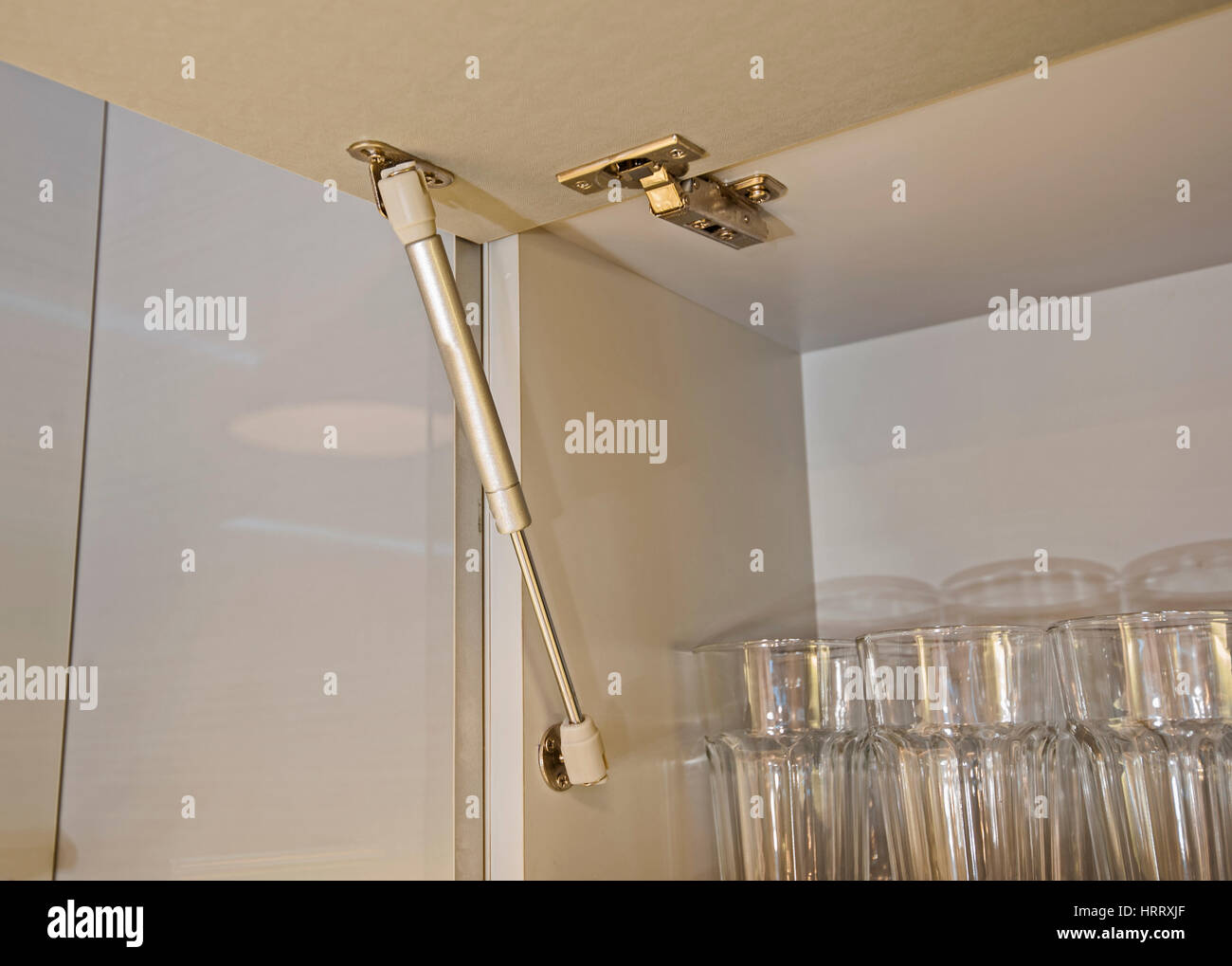 Closeup detail of an actuator hydraulic hinge on kitchen cupboard door ...