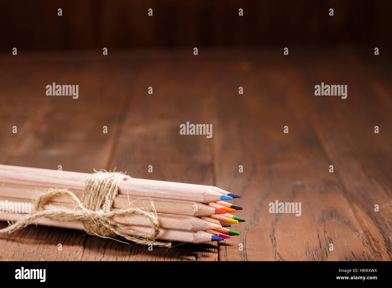 Set of sharp colorful pencils tied with wool rope on a wooden blank ...