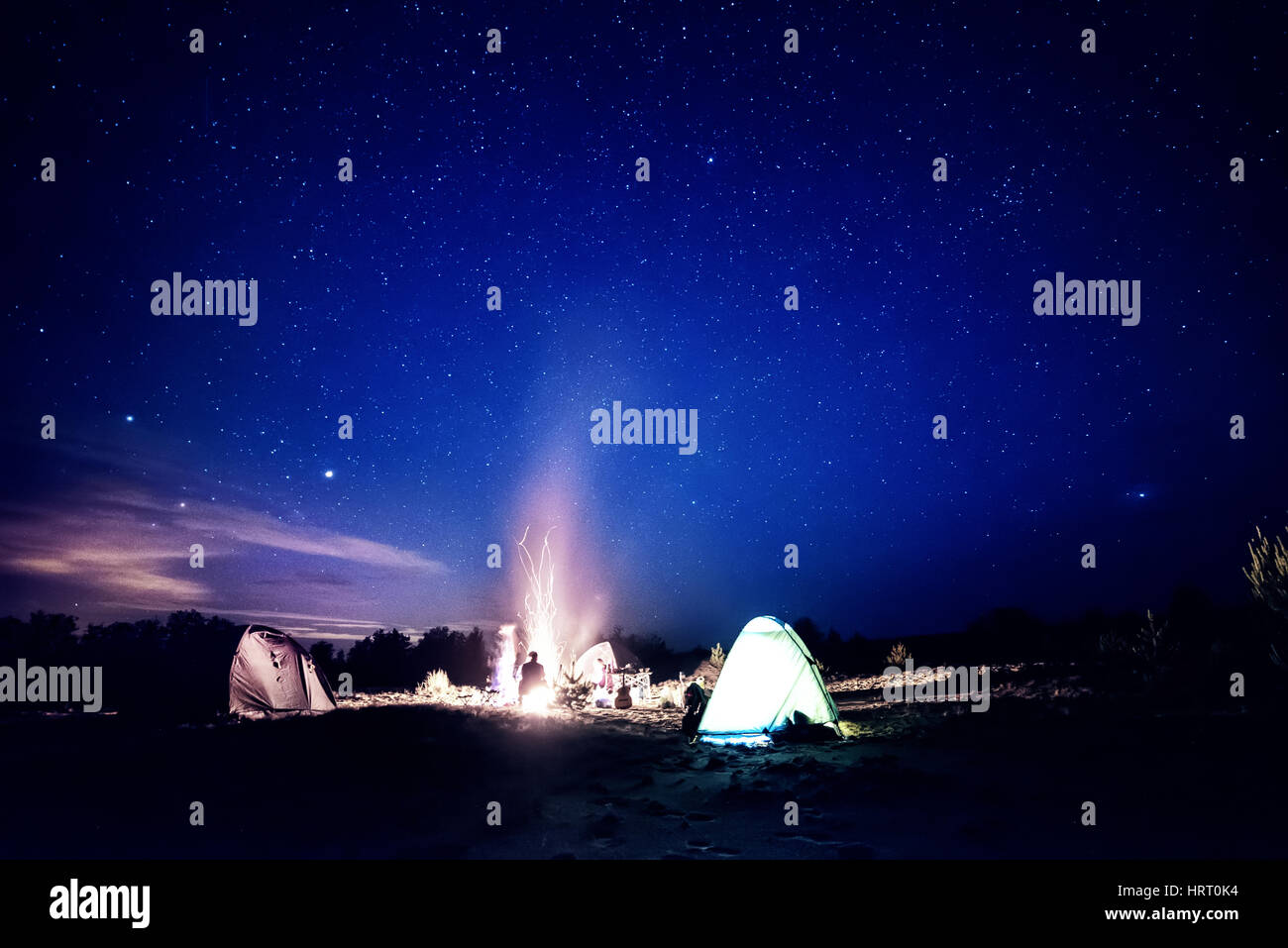 Camping fire under the amazing blue starry sky with a lot of shining ...