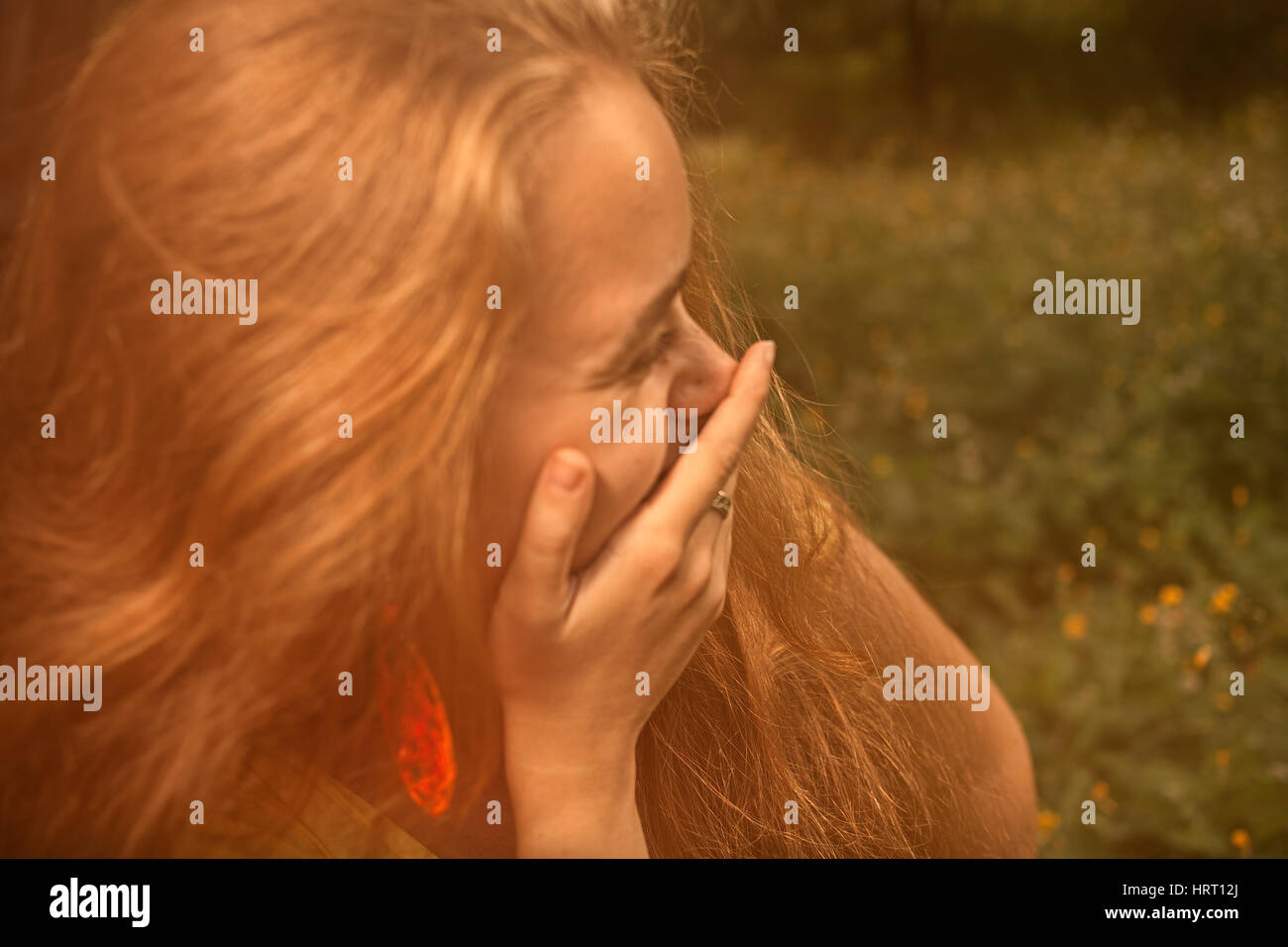 Blond haired girl hiding her smile by hand and looking away retro color ...