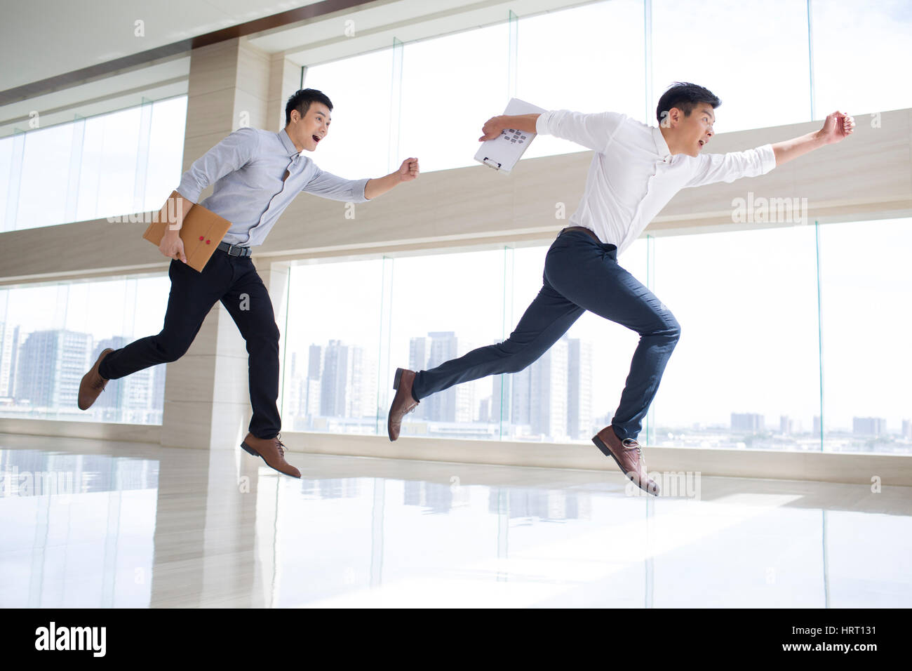 Young businessmen running in office building Stock Photo, Royalty Free ...