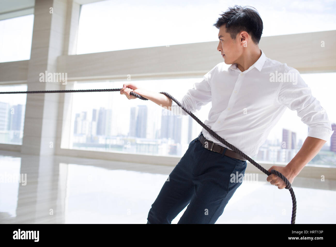 Young businessman pulling rope Stock Photo - Alamy