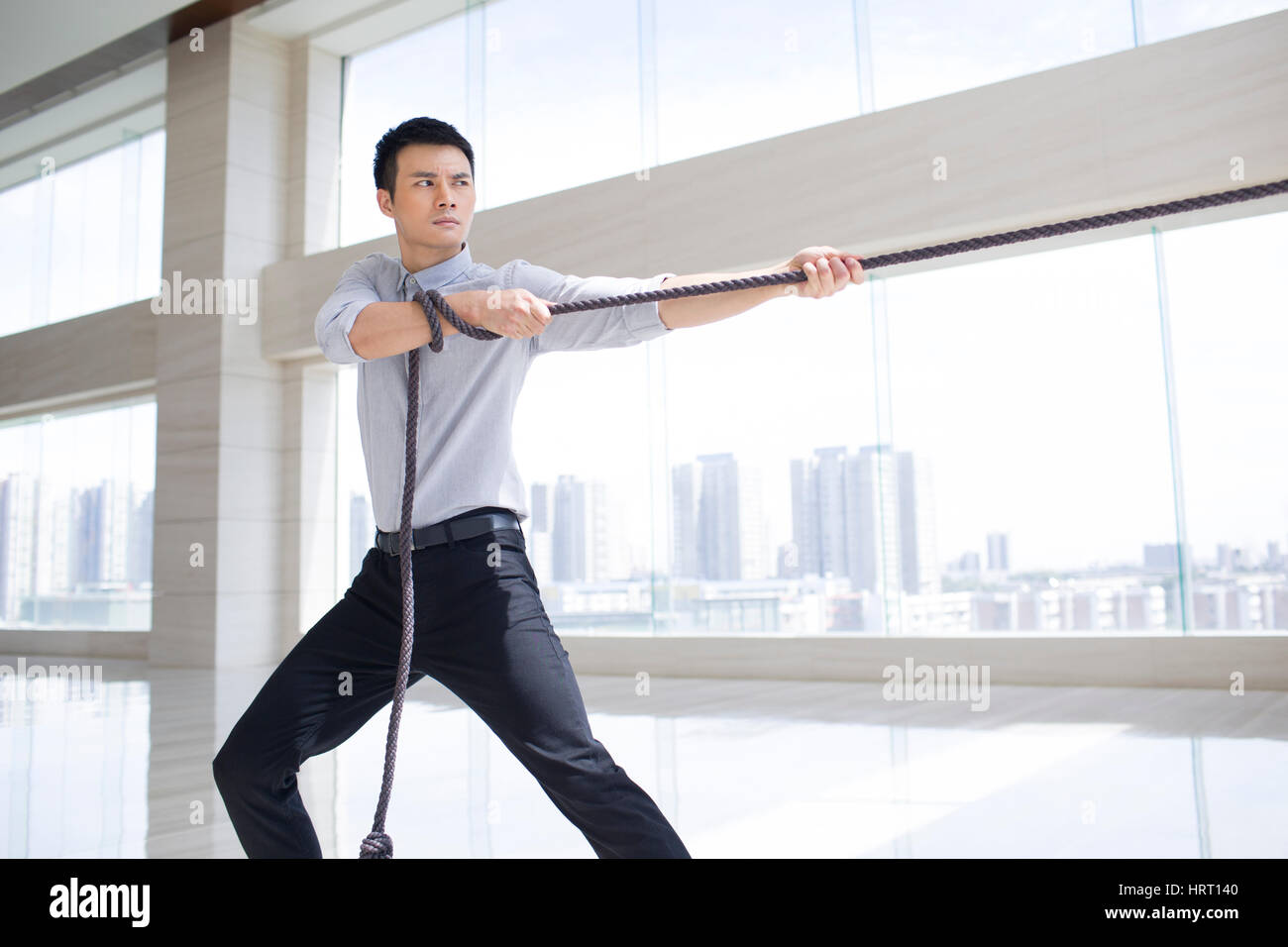 Young businessman pulling rope Stock Photo - Alamy