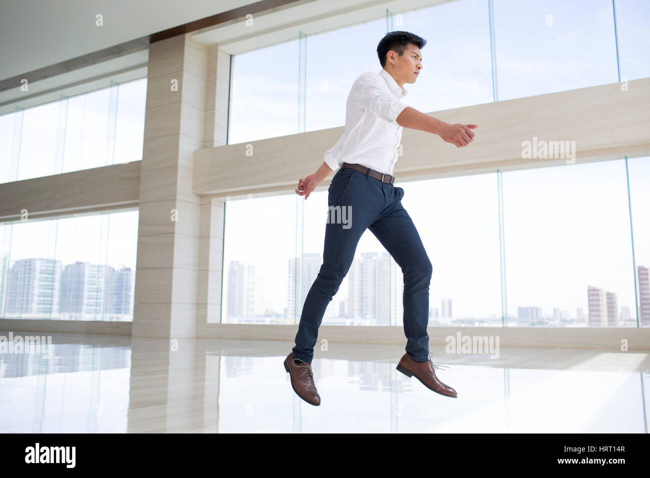 Young businessman jumping in office building Stock Photo - Alamy