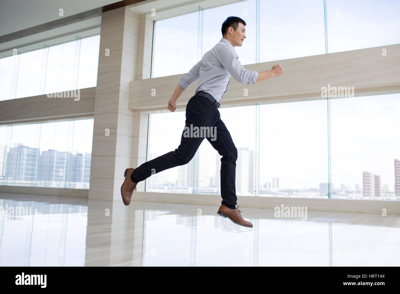 Young businessman running in office building Stock Photo - Alamy