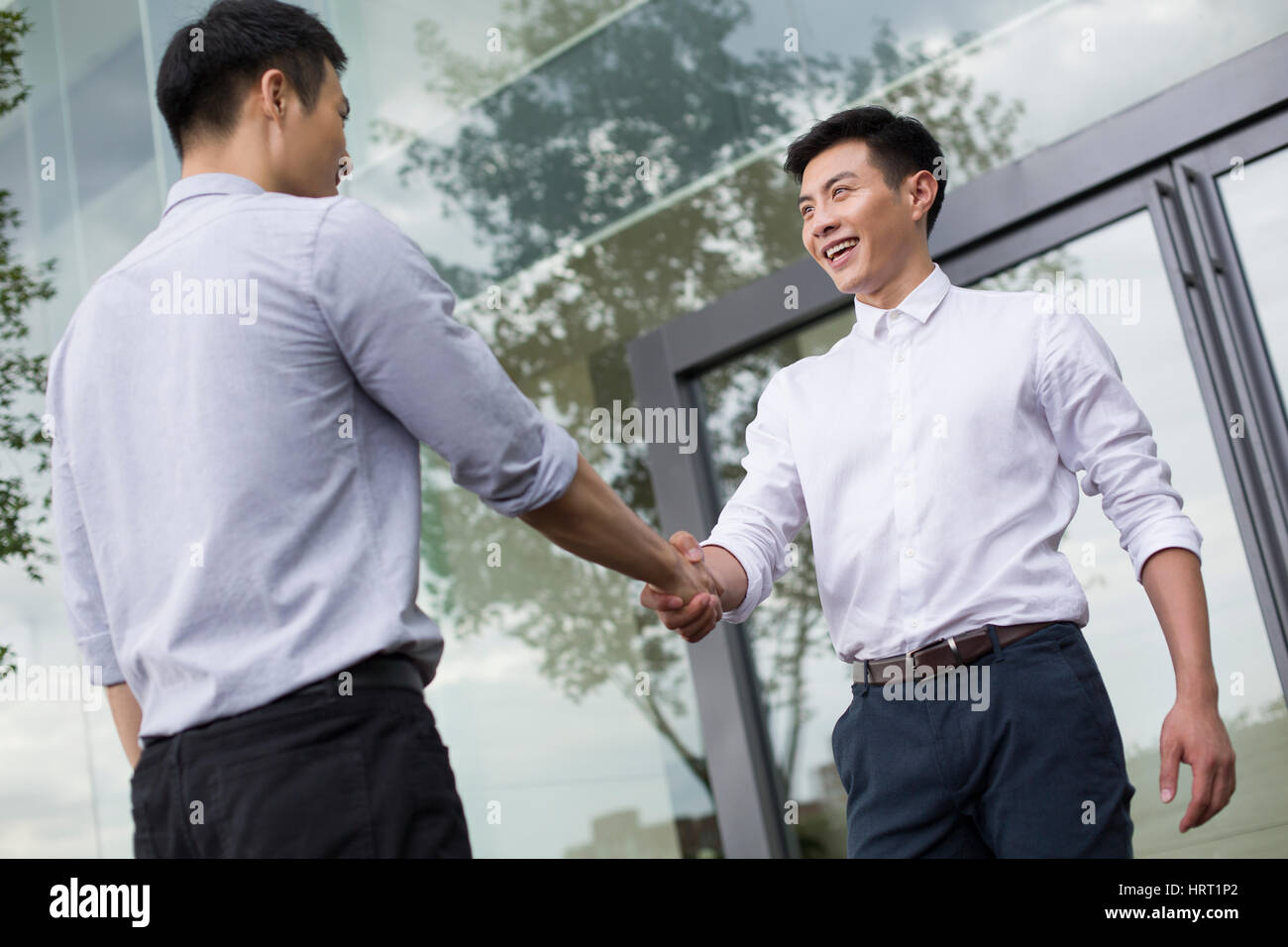 Young business person shaking hands outdoors Stock Photo - Alamy