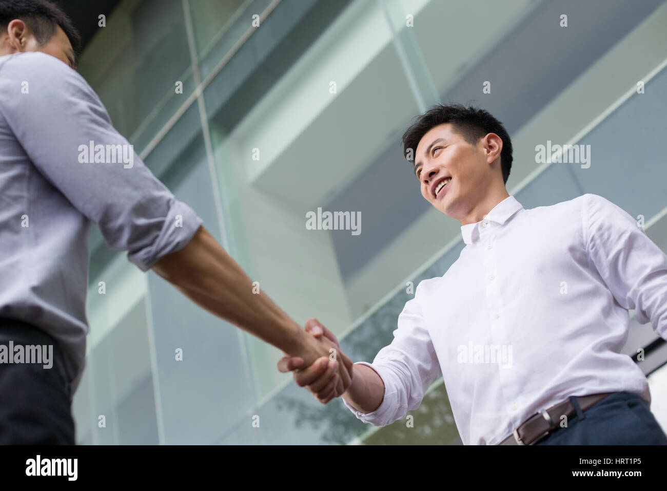 Young business person shaking hands outdoors Stock Photo - Alamy