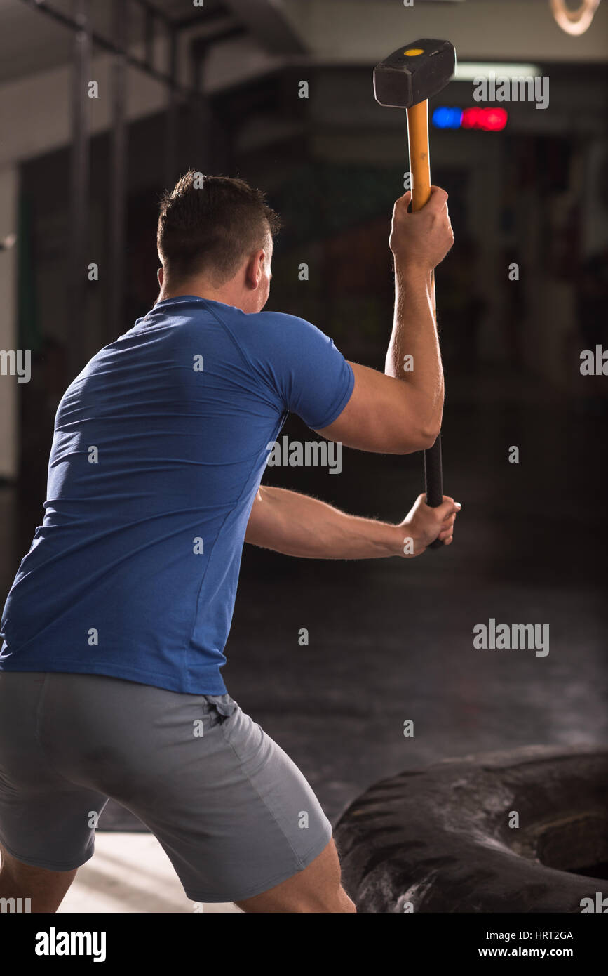 Sledgehammer Tire Hits young muscular man workout at gym with hammer ...