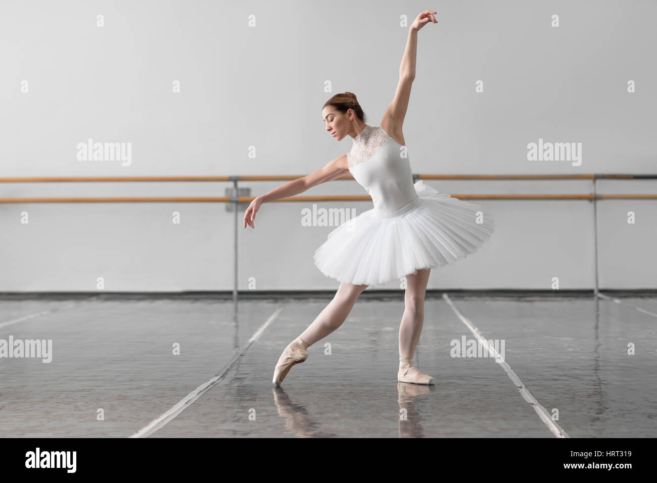 Beautiful female ballet dancer in ballet class, barre and white wall on ...