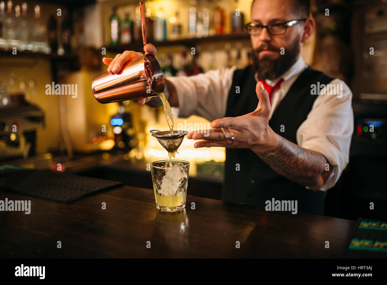 Barman flaring behind bar counter. Restaurant shelves with alcoholic ...