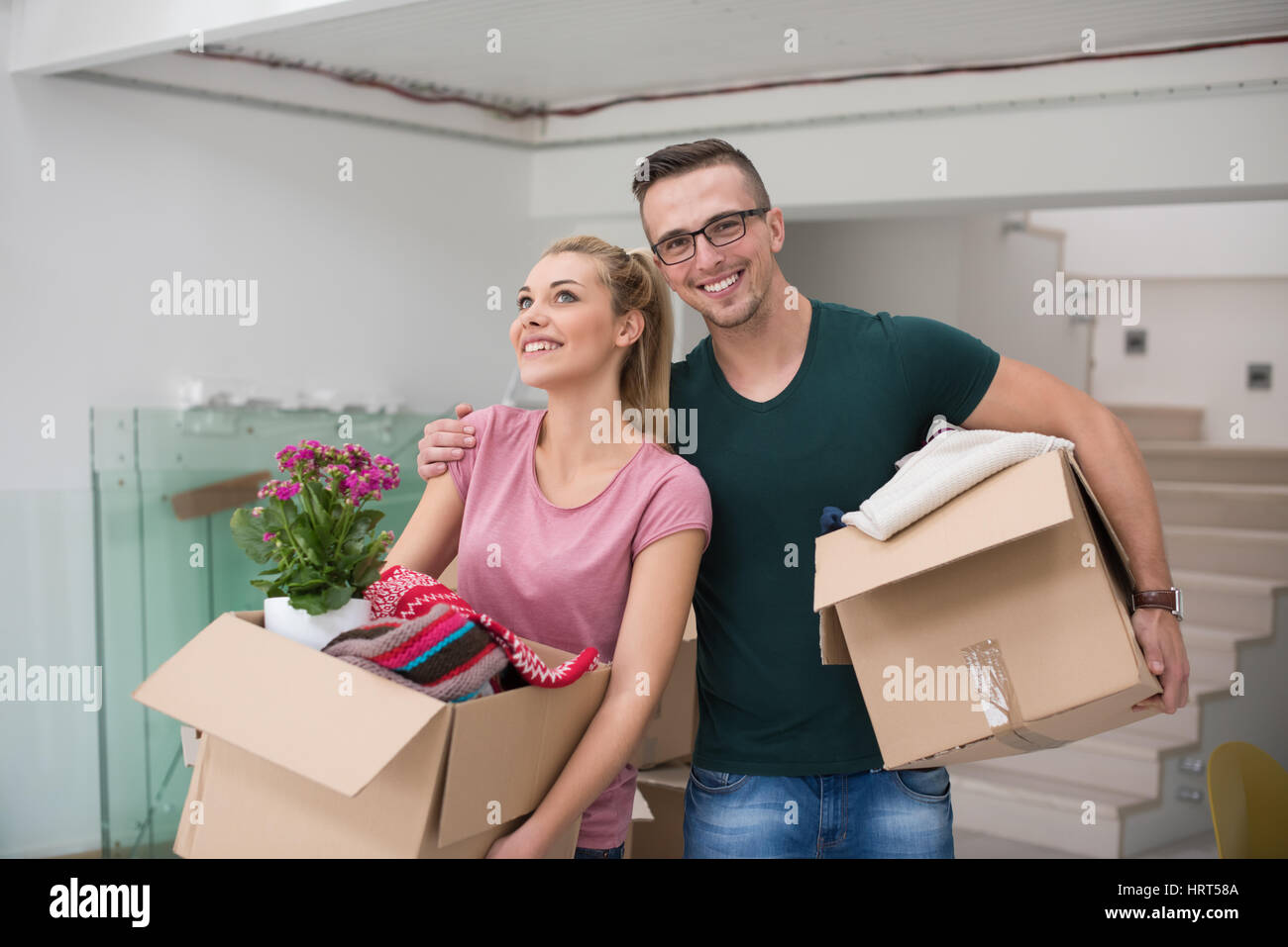 Happy young couple unpacking or packing boxes and moving into a new ...