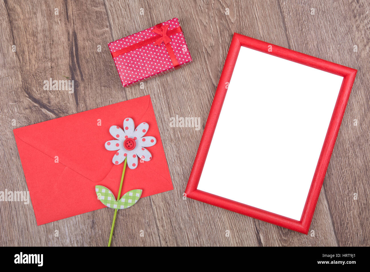 Red picture frame and darling, envelope and flower on a wooden ...