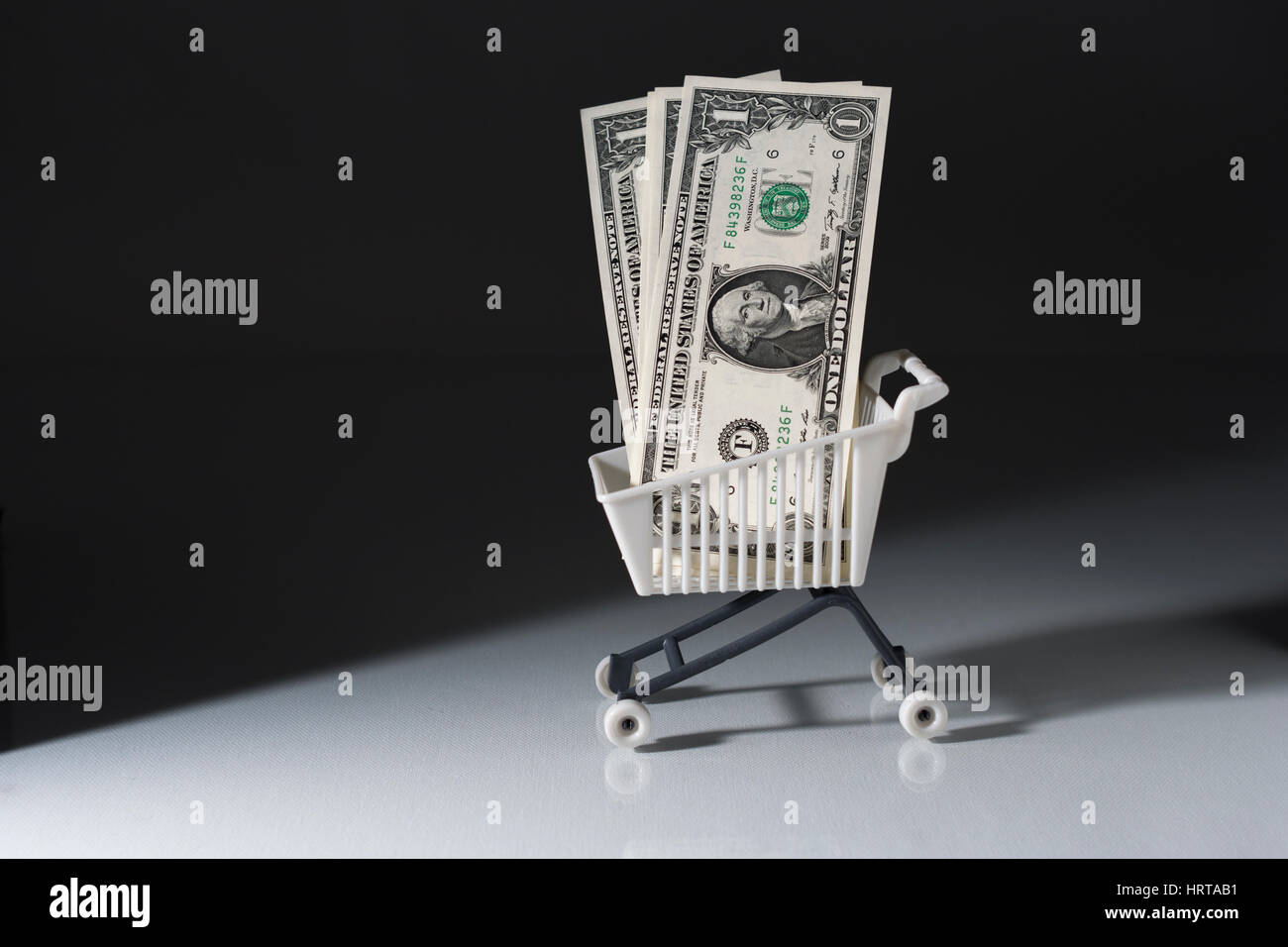 US $1 bills / banknotes in shopping cart / trolley against a dark ...