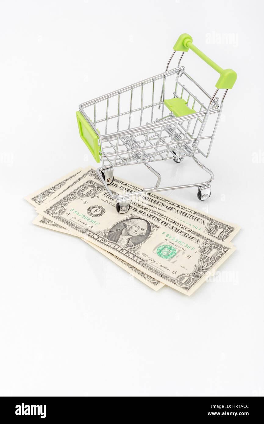 Shopping cart over several US $1 / one dollar banknotes on a light ...