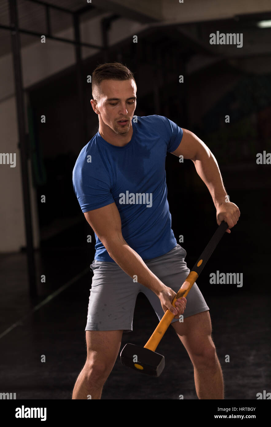 Sledgehammer Tire Hits young muscular man workout at gym with hammer ...