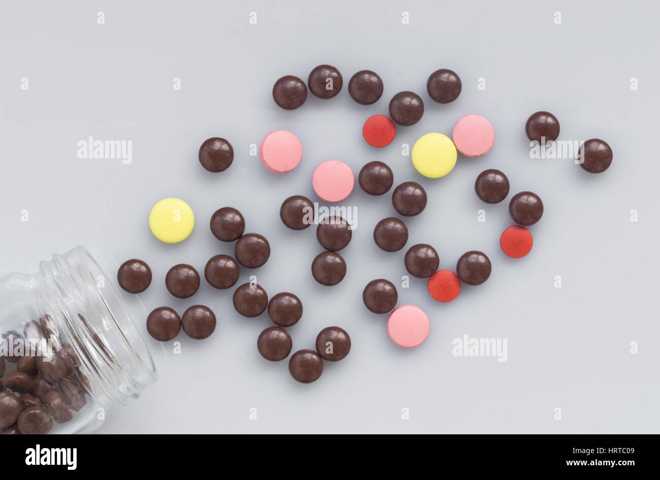 Different pills spill out of a glass jar on a light surface Stock Photo ...