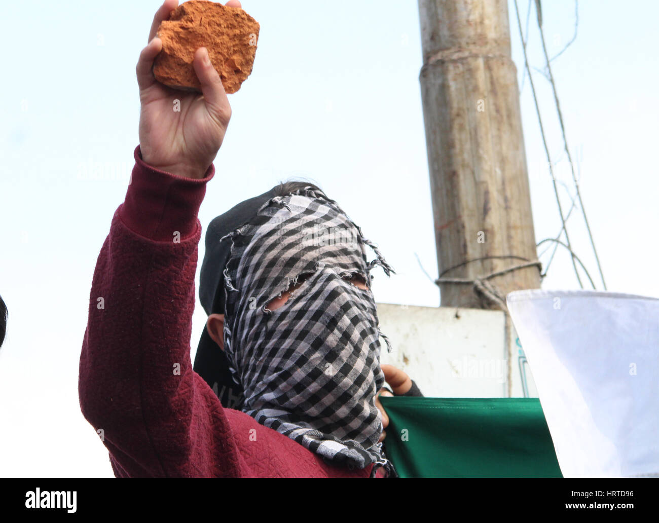 Srinagar, Kashmir. 03rd Mar, 2017. A Masked youth holding stones in ...