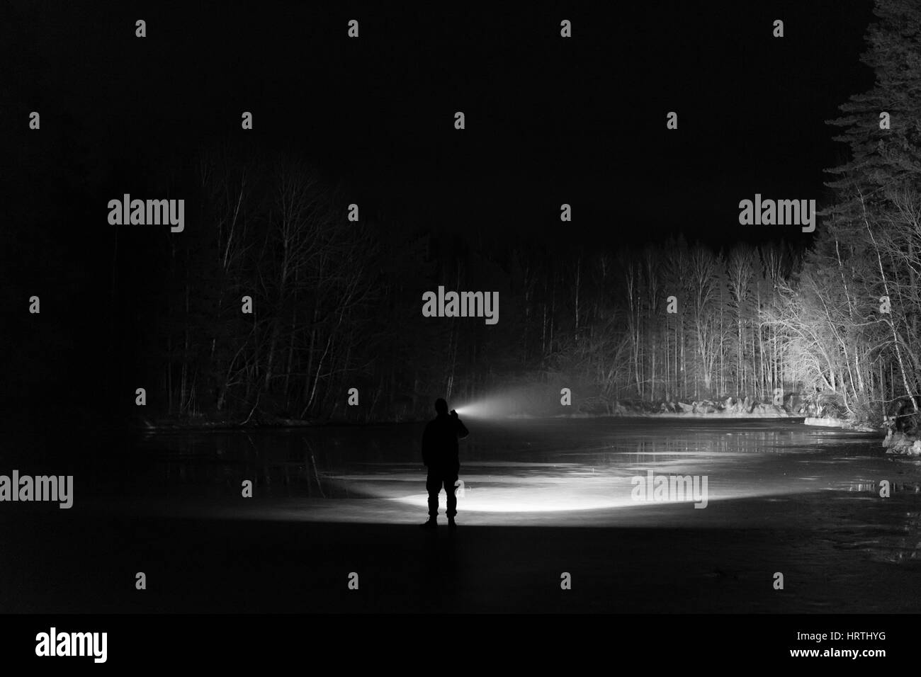 Human with flashlight standing on a ice lake at night. Sweden ...