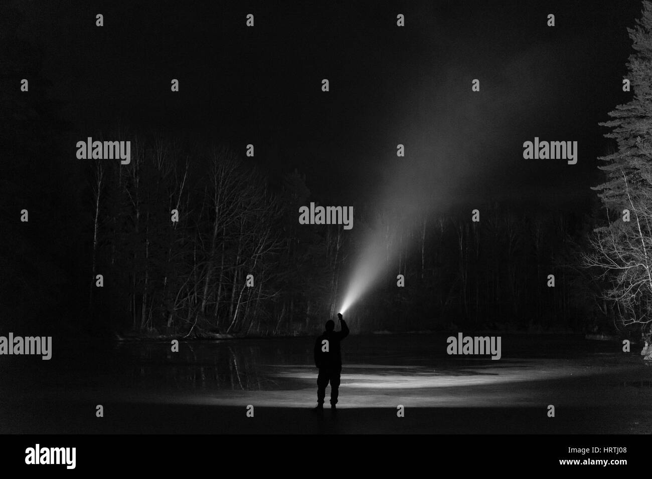 Human with flashlight standing on a ice lake at night. Sweden ...