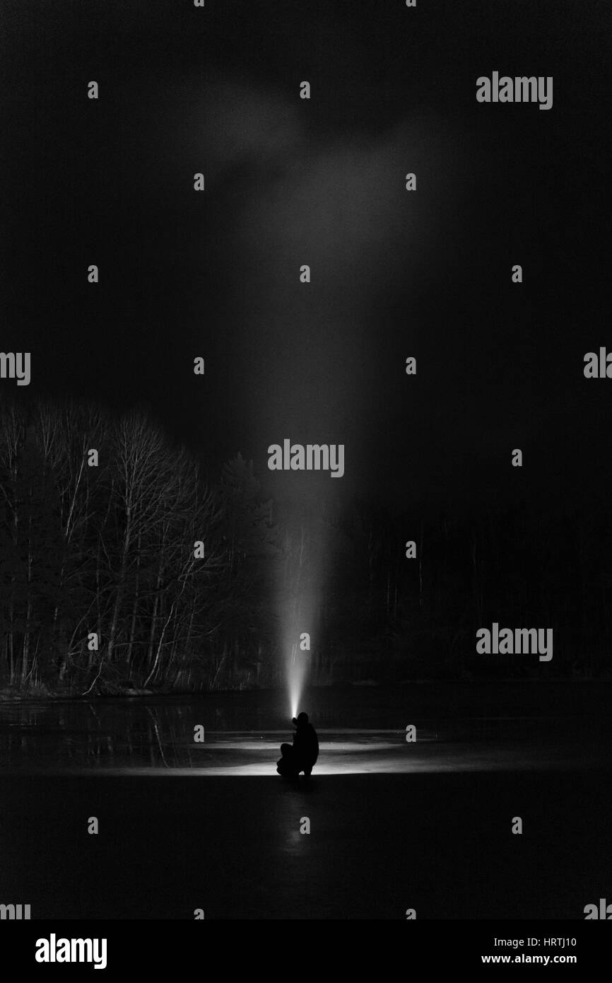 Human with flashlight standing on a ice lake at night. Sweden ...