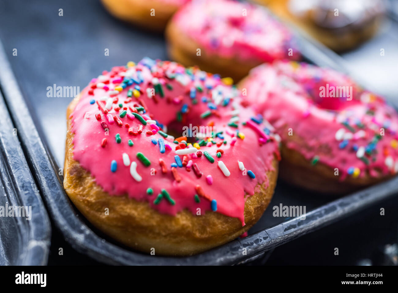 Pink iced donuts with rainbow sprinkles Stock Photo - Alamy