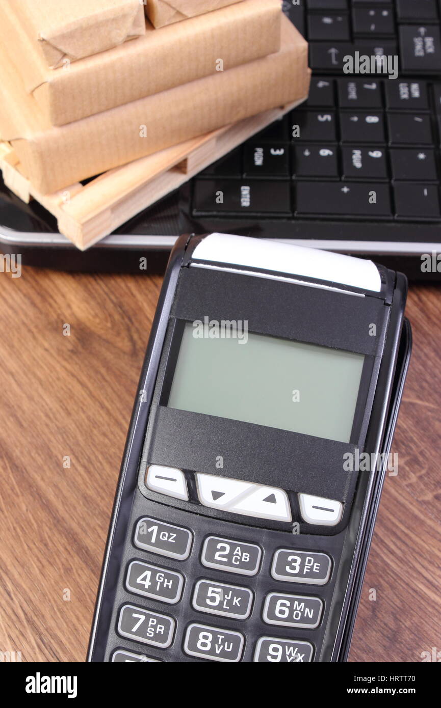 Payment terminal, laptop and small wrapped boxes on wooden pallet ...