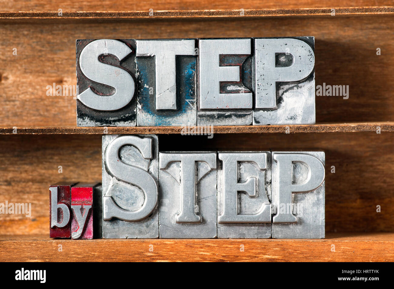 step by step phrase made from metallic letterpress type on wooden tray ...