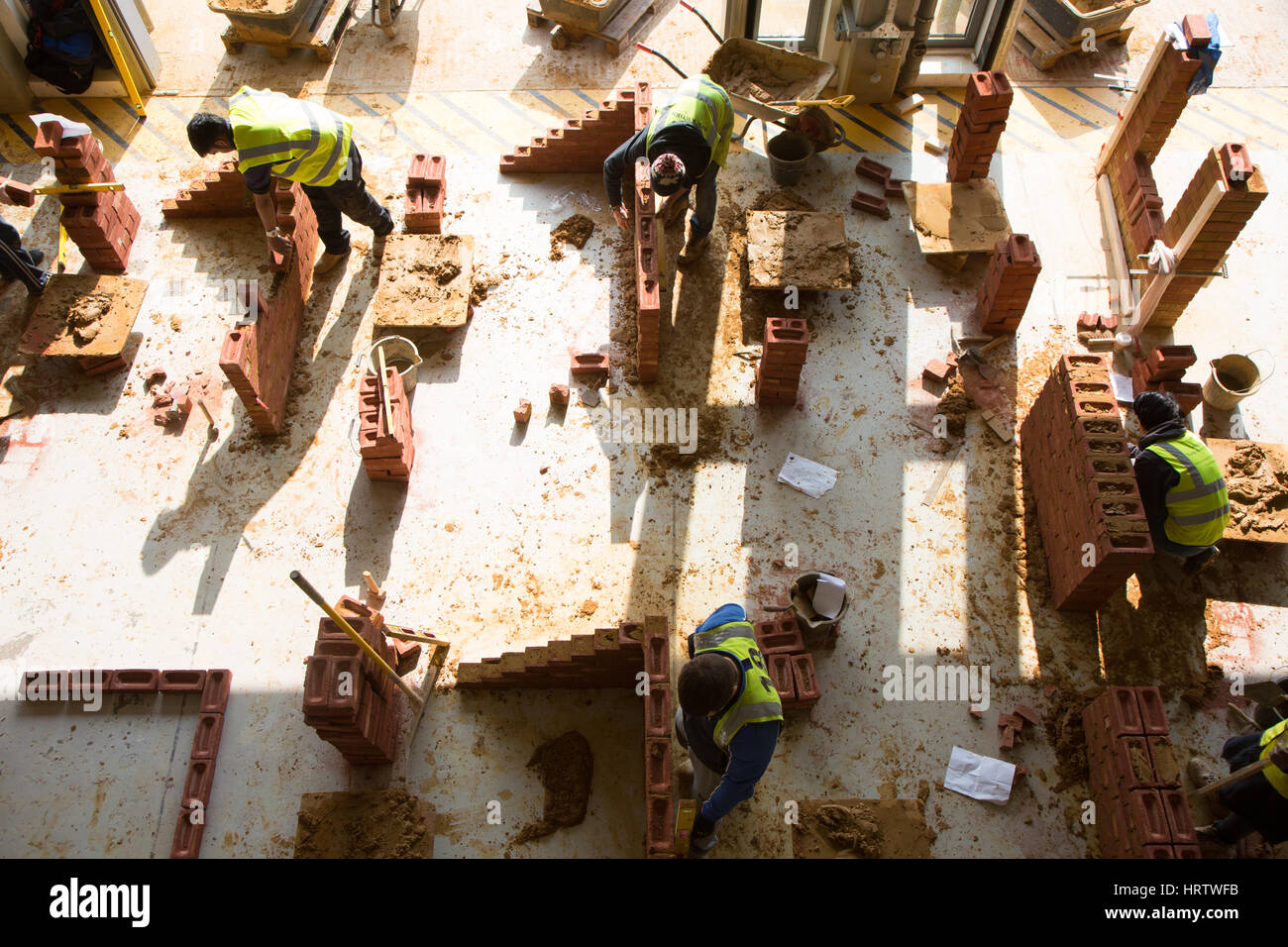 Apprentice builders learn how to construct a wall using bricks and ...