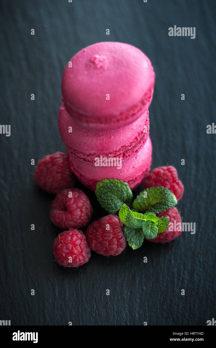 pink macaroons with raspberries on black background Stock Photo - Alamy