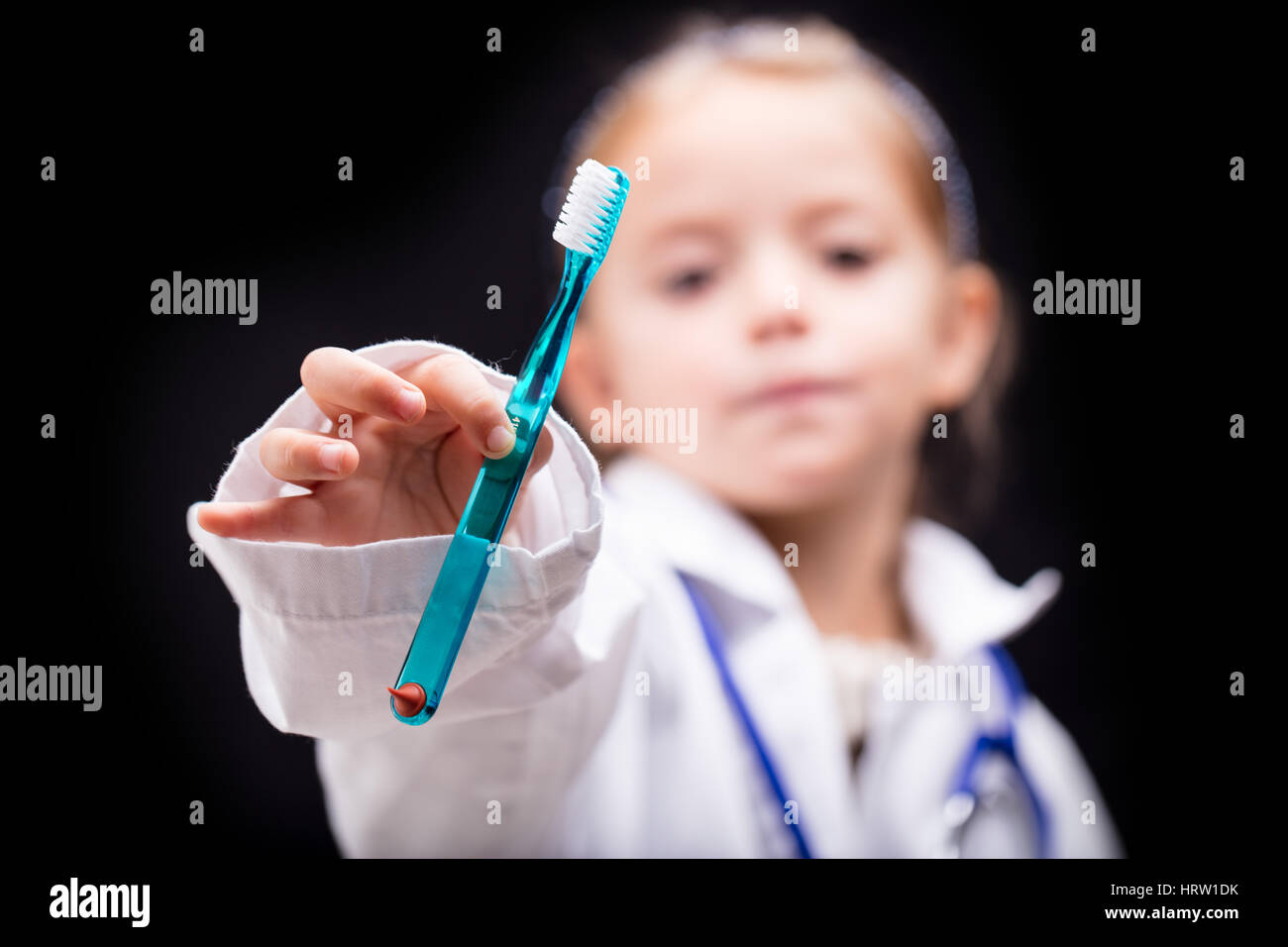 Little girl holding out a blue plastic toothbrush towards the camera in ...