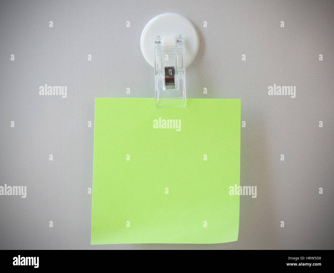 Light green post it clip by clip magnet on gray refrigerator background ...