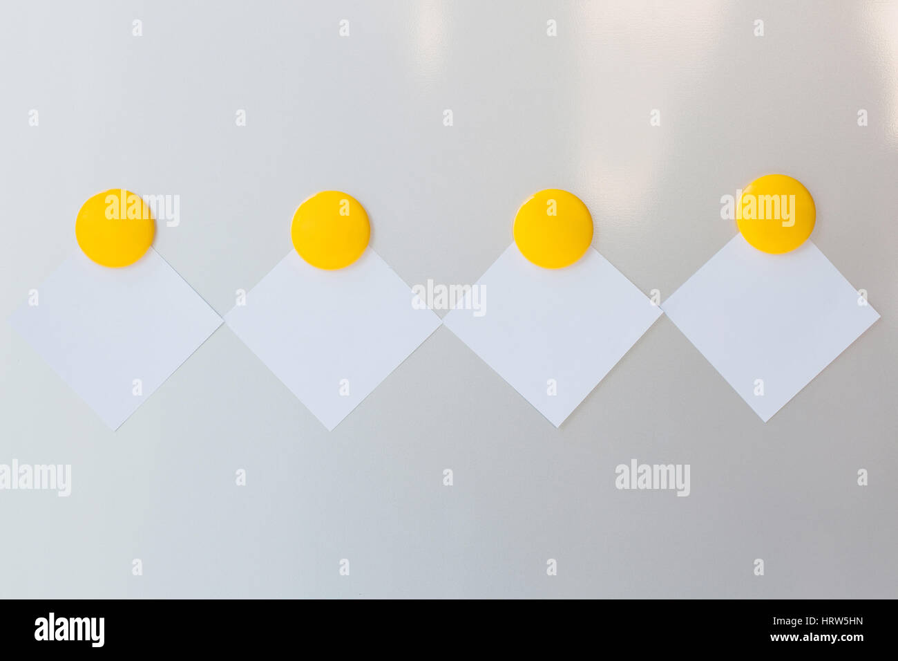 Yellow magnet put on on blank paper gray refrigerator background ...
