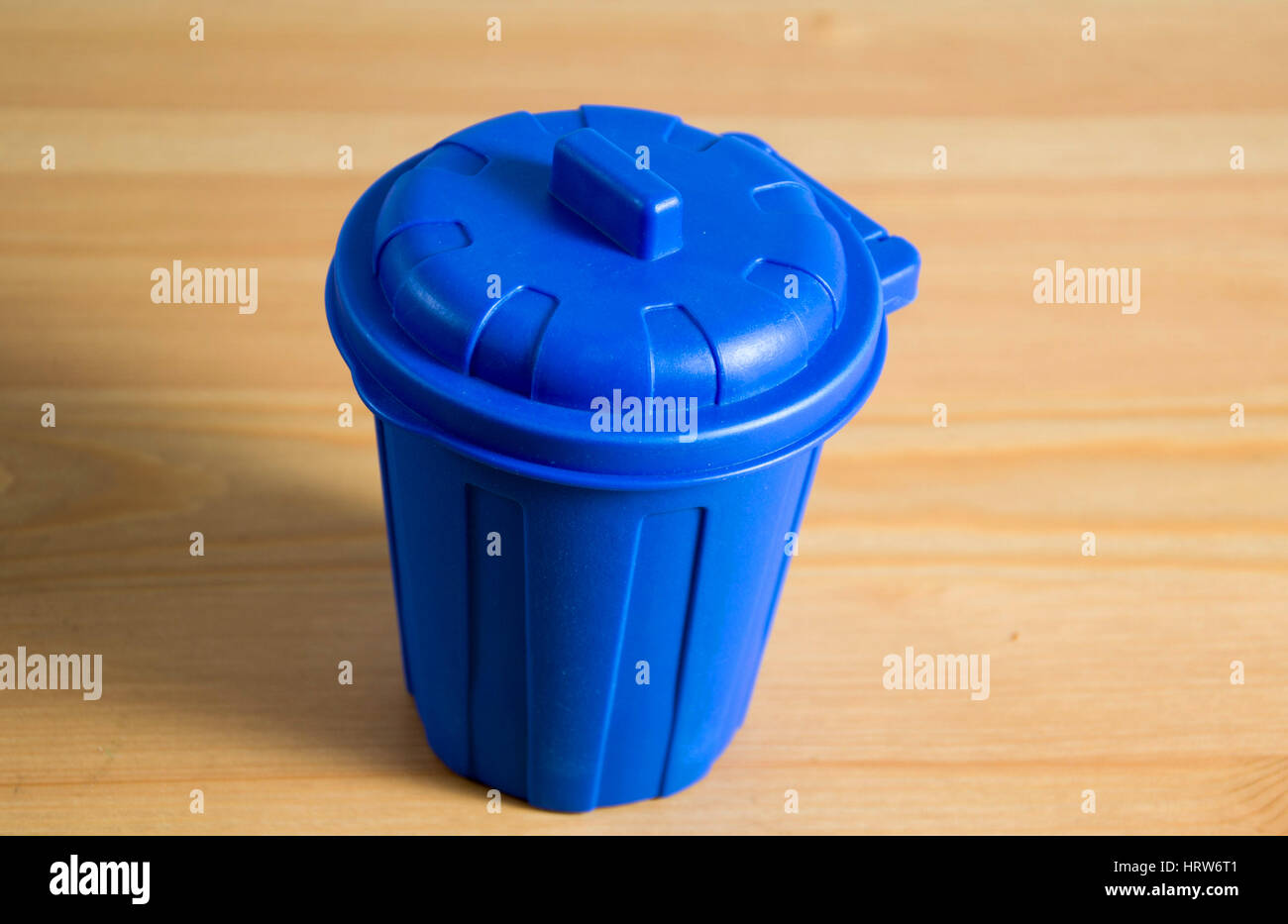 a blue garbage can on wooden background Stock Photo - Alamy