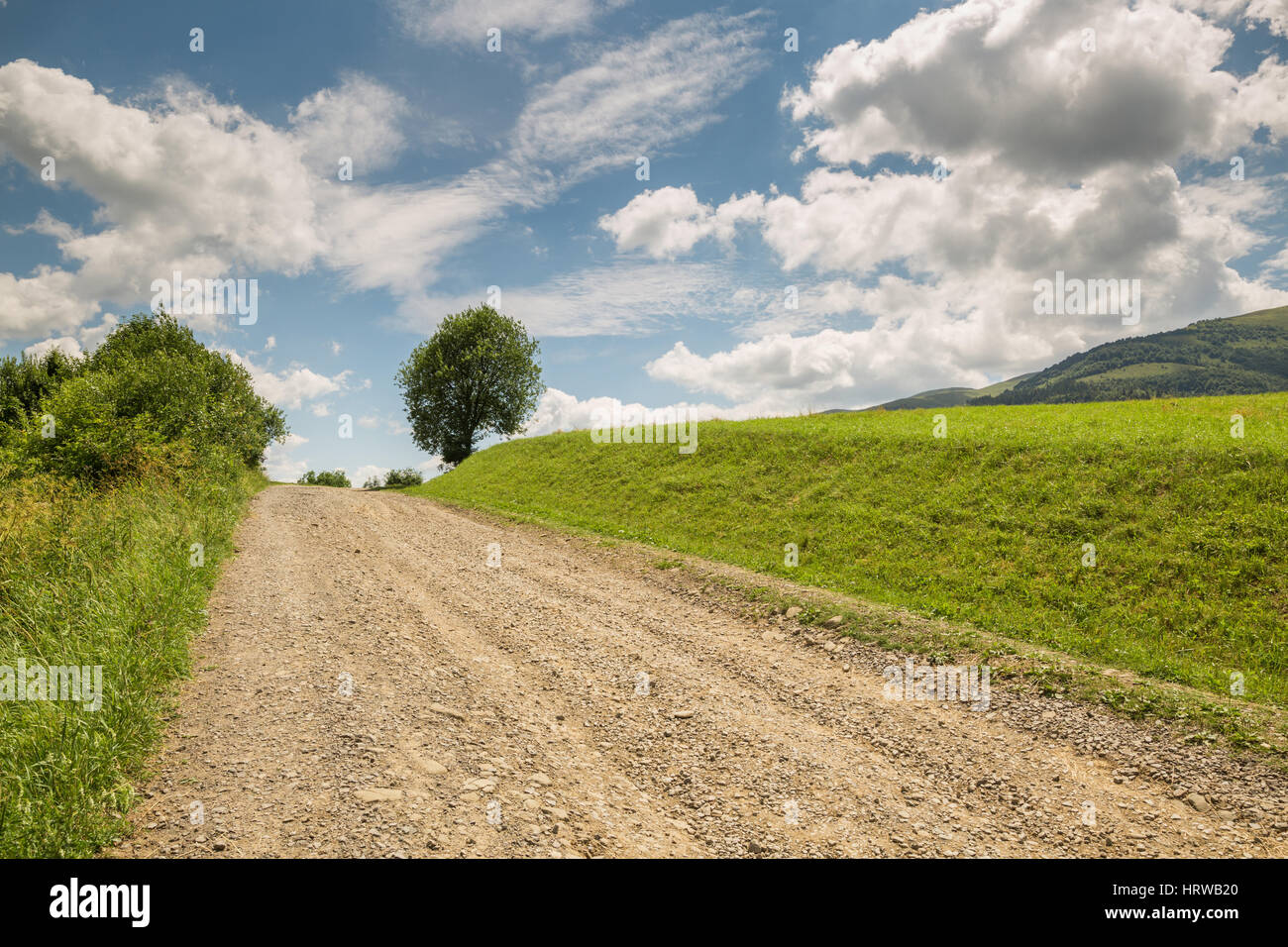 road with gravel stretches up the green hill Stock Photo - Alamy