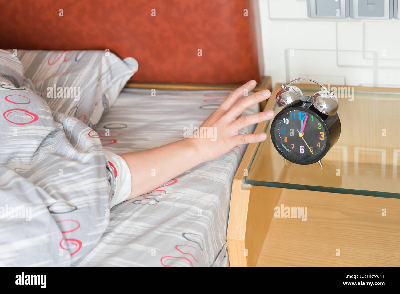 lazy man using a hand to grab a ringing clock in noon time Stock Photo ...