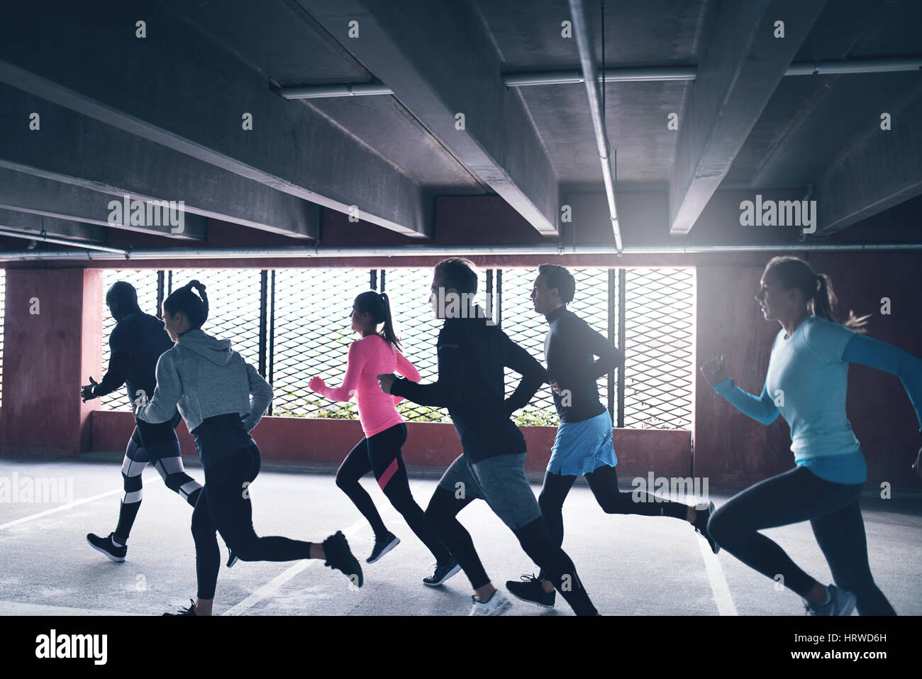 Side view of group of athletes running race over big window in parking ...