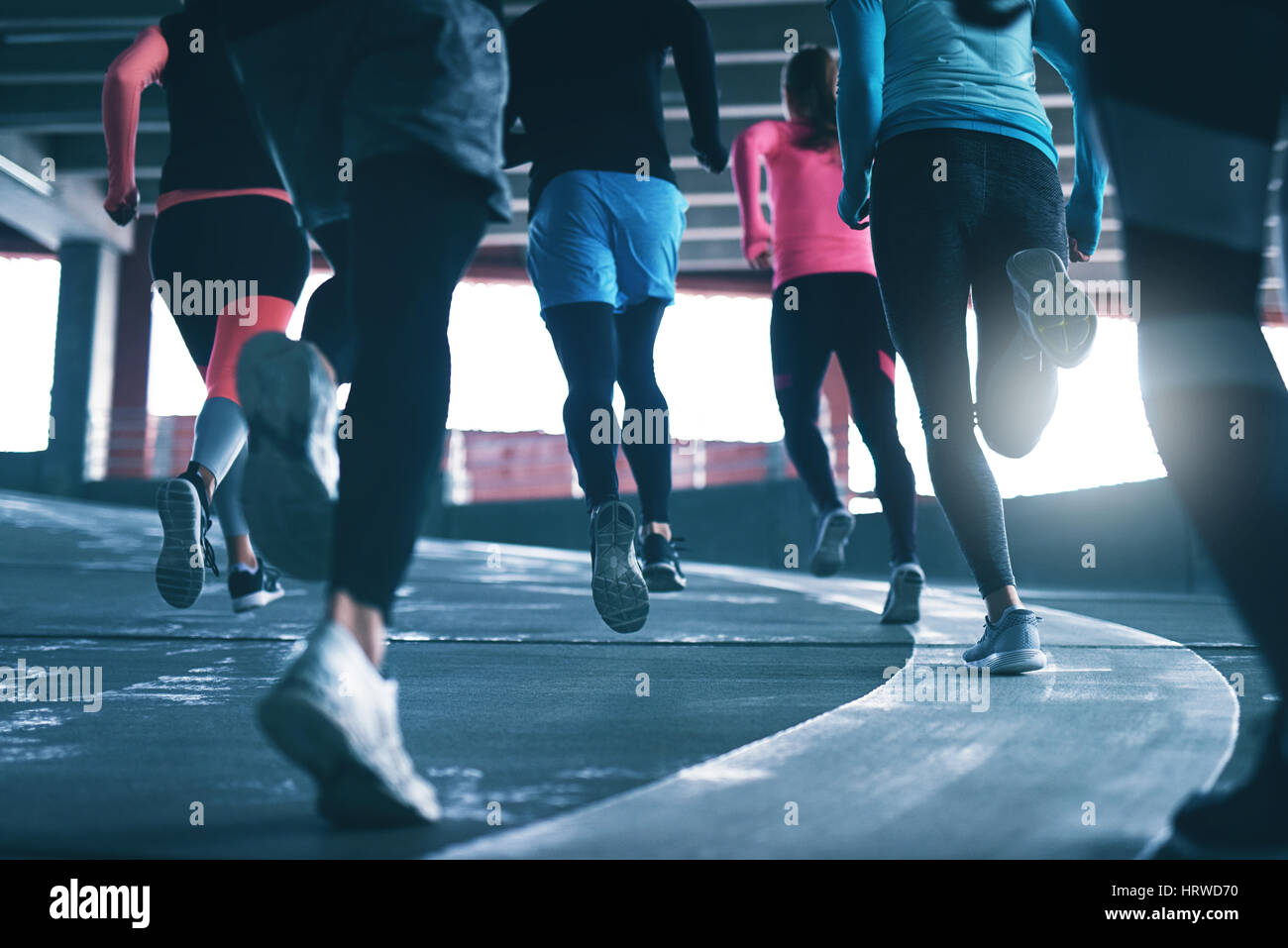 Back view of young sportspeople running on race track at sports ground ...