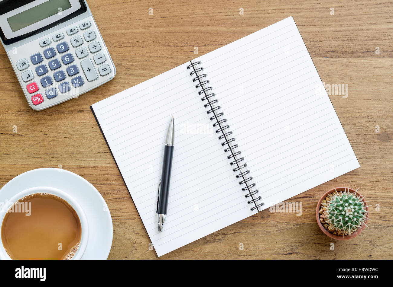 Wooden desk table with notebook, pen, calculator and cup of coffee. Top ...